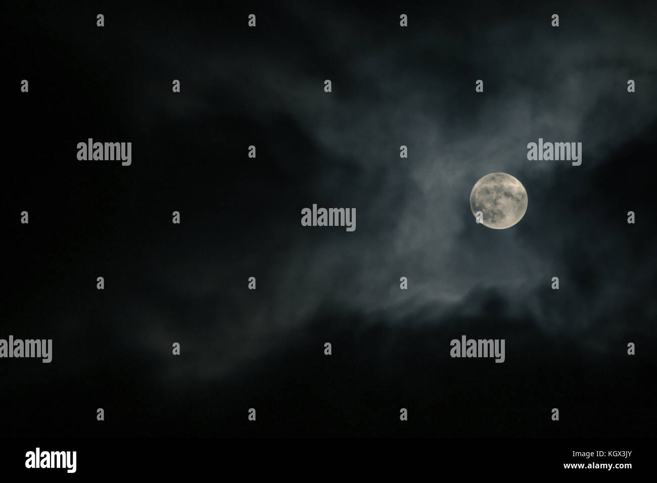 A full moon behind the clouds during the cloudy night. It is hiding and ...