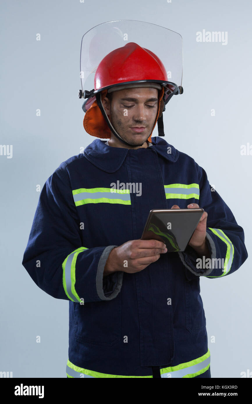 Smiling fireman using digital tablet against white background Stock ...