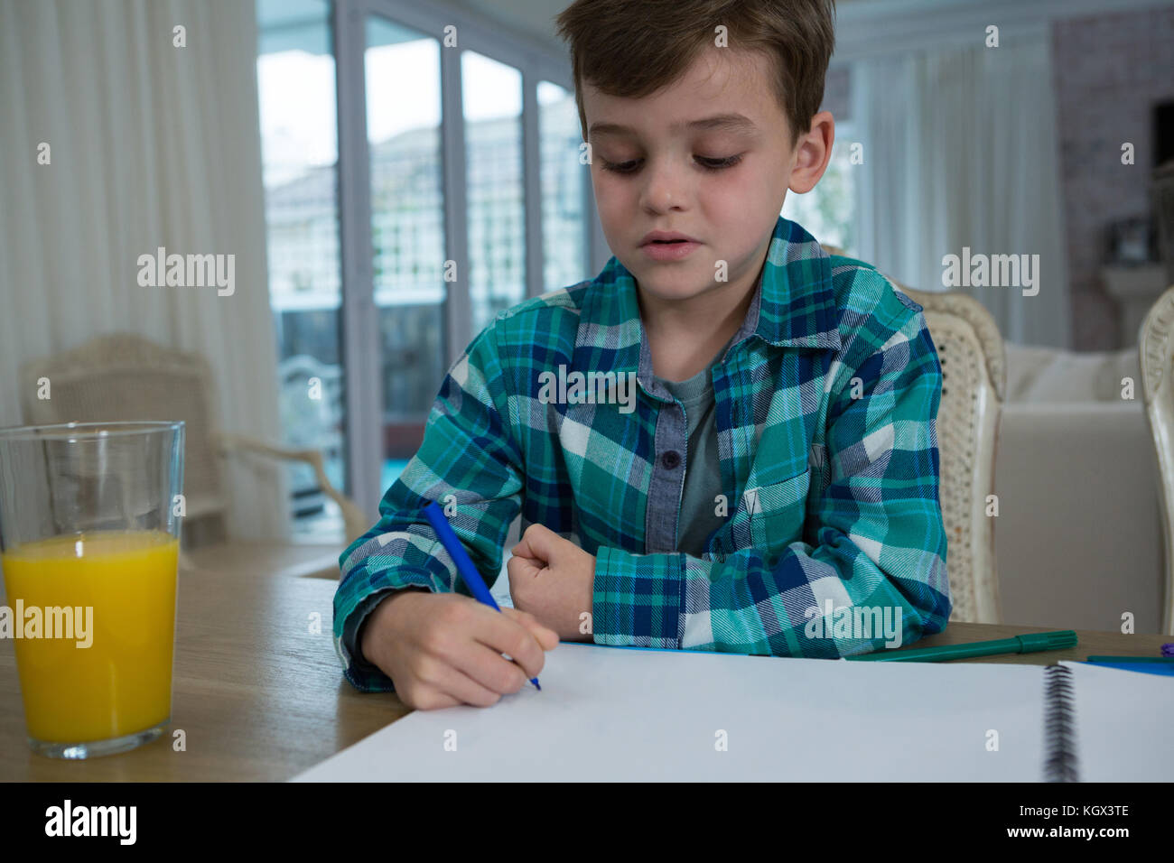 Boy doing homework at table in living room Stock Photo - Alamy