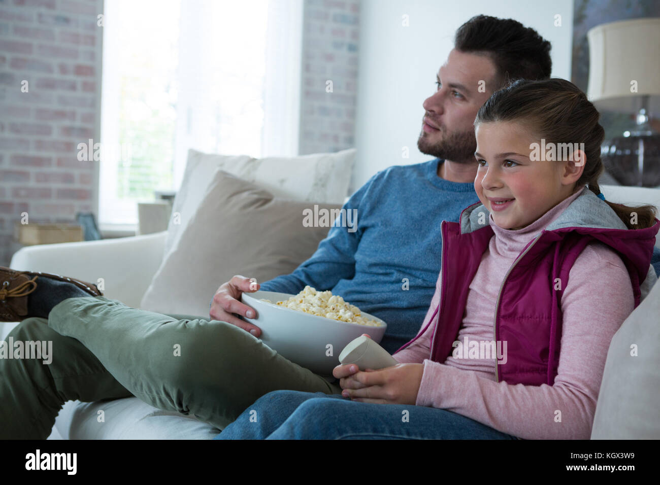 Father and daughter watching television in living room at home Stock ...