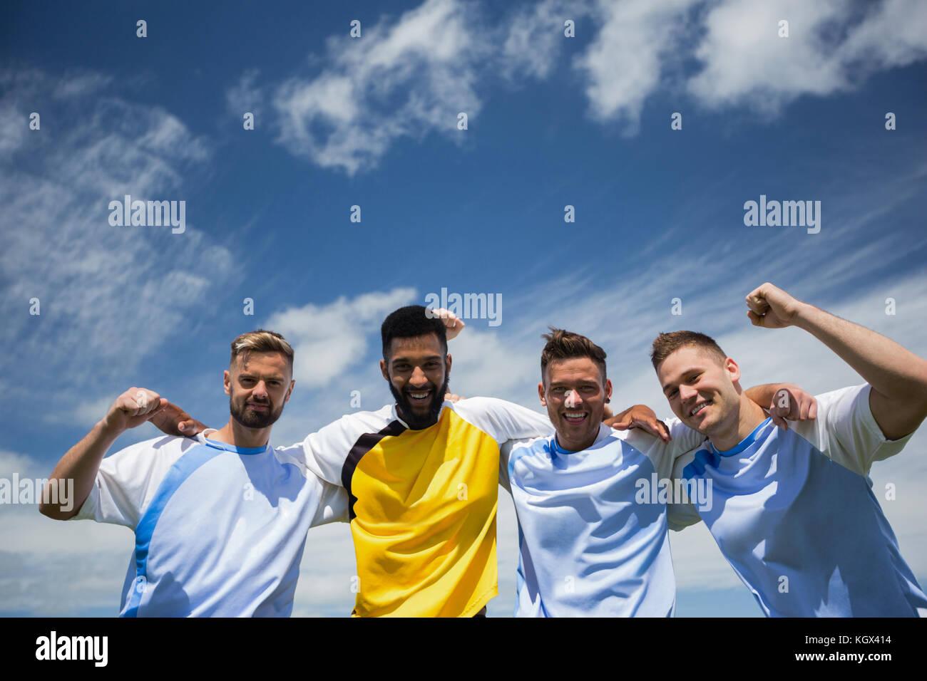 Portrait of excited football players standing together with arm around ...
