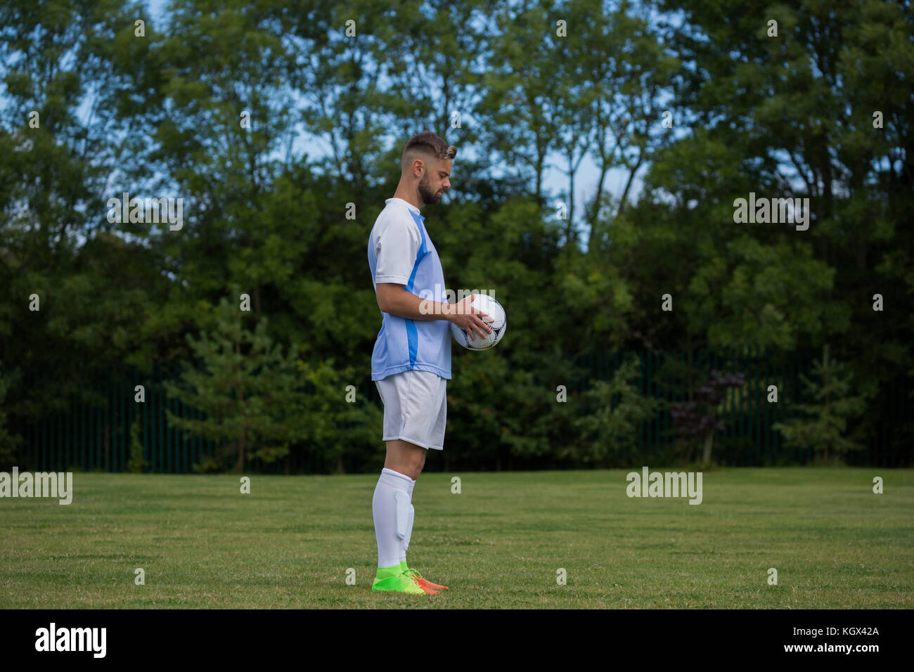 Side view of football player holding soccer in the ground Stock Photo ...
