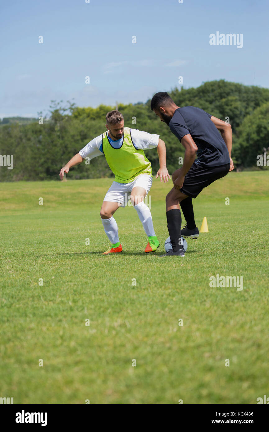 Football players dribbling the soccer on the football ground on a sunny ...