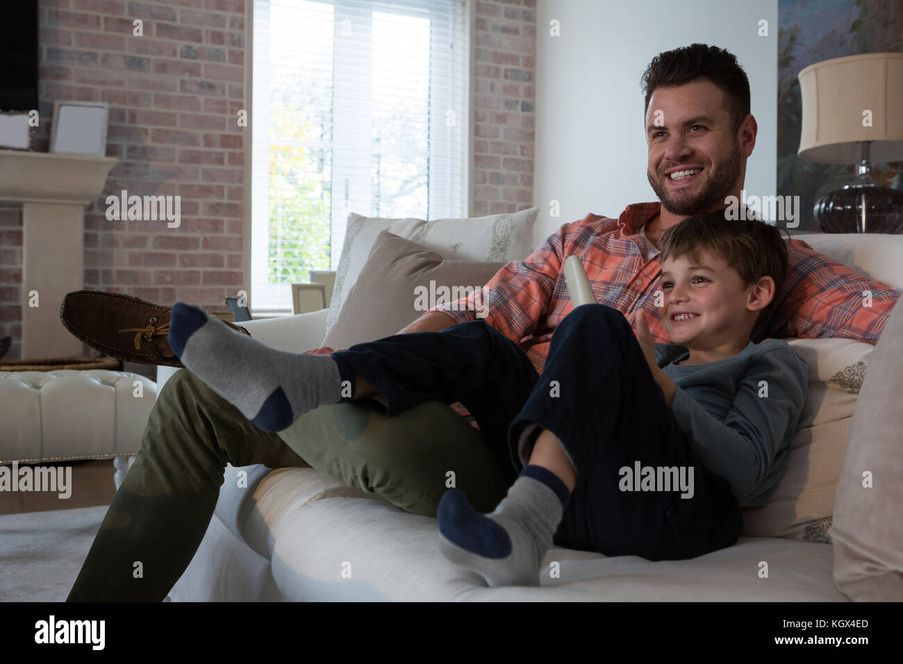 Happy father and son watching television in living room Stock Photo - Alamy