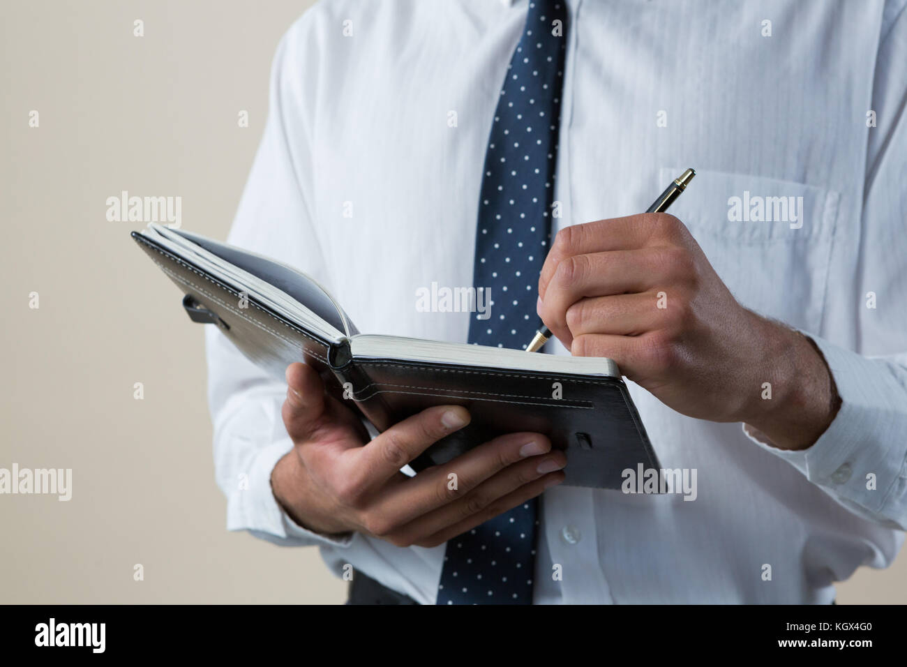 Mid section of executive writing on diary against white background ...
