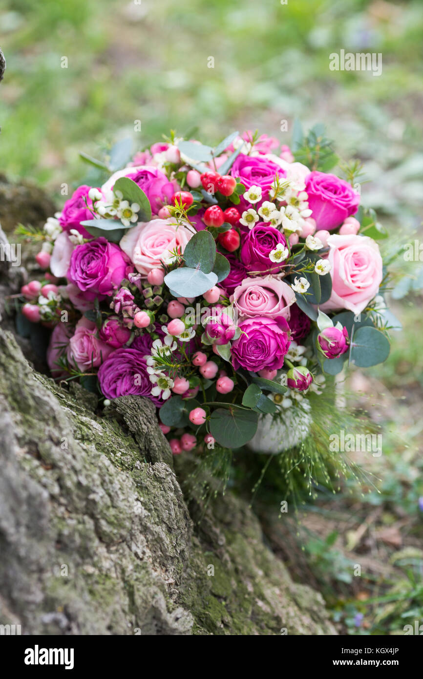 Close-up of pink roses wedding bouquet placed outdoors next to a tree ...
