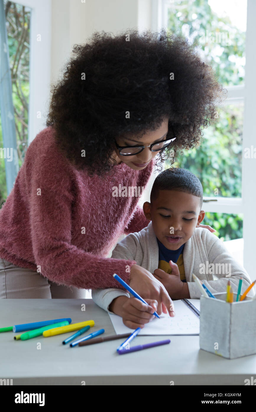Mother helping her son in doing homework at home Stock Photo - Alamy