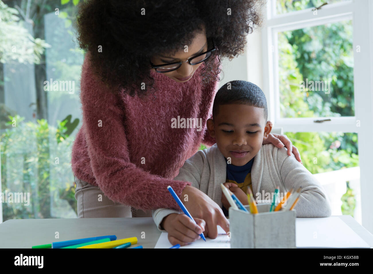 Mother helping her son in doing homework at home Stock Photo - Alamy