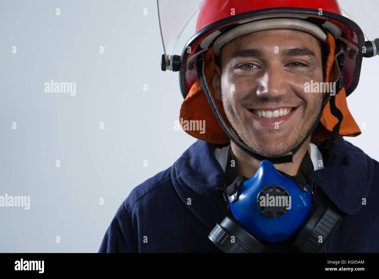 Smiling fireman looking at camera against white background Stock Photo ...