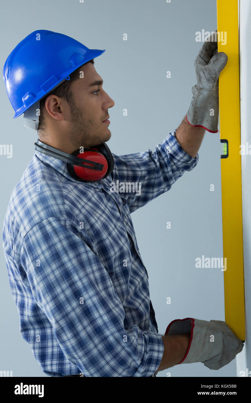 Male architect measuring wall with engineer scale against white ...