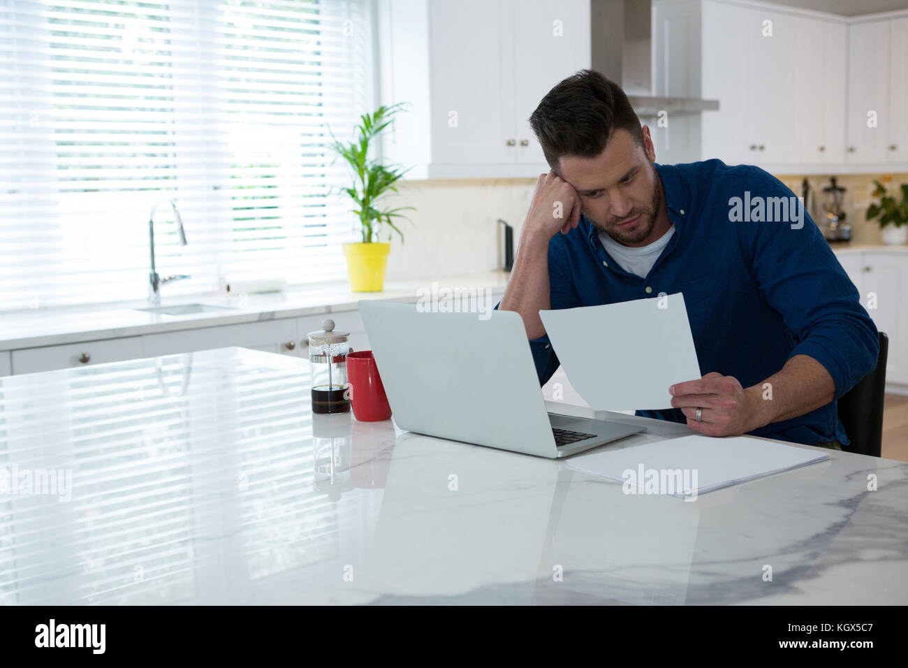 Man looking at bill in kitchen at home Stock Photo - Alamy