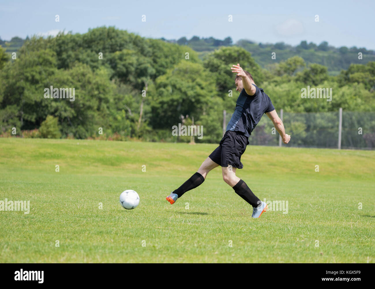 Football player kicking the soccer on the football ground on a sunny ...