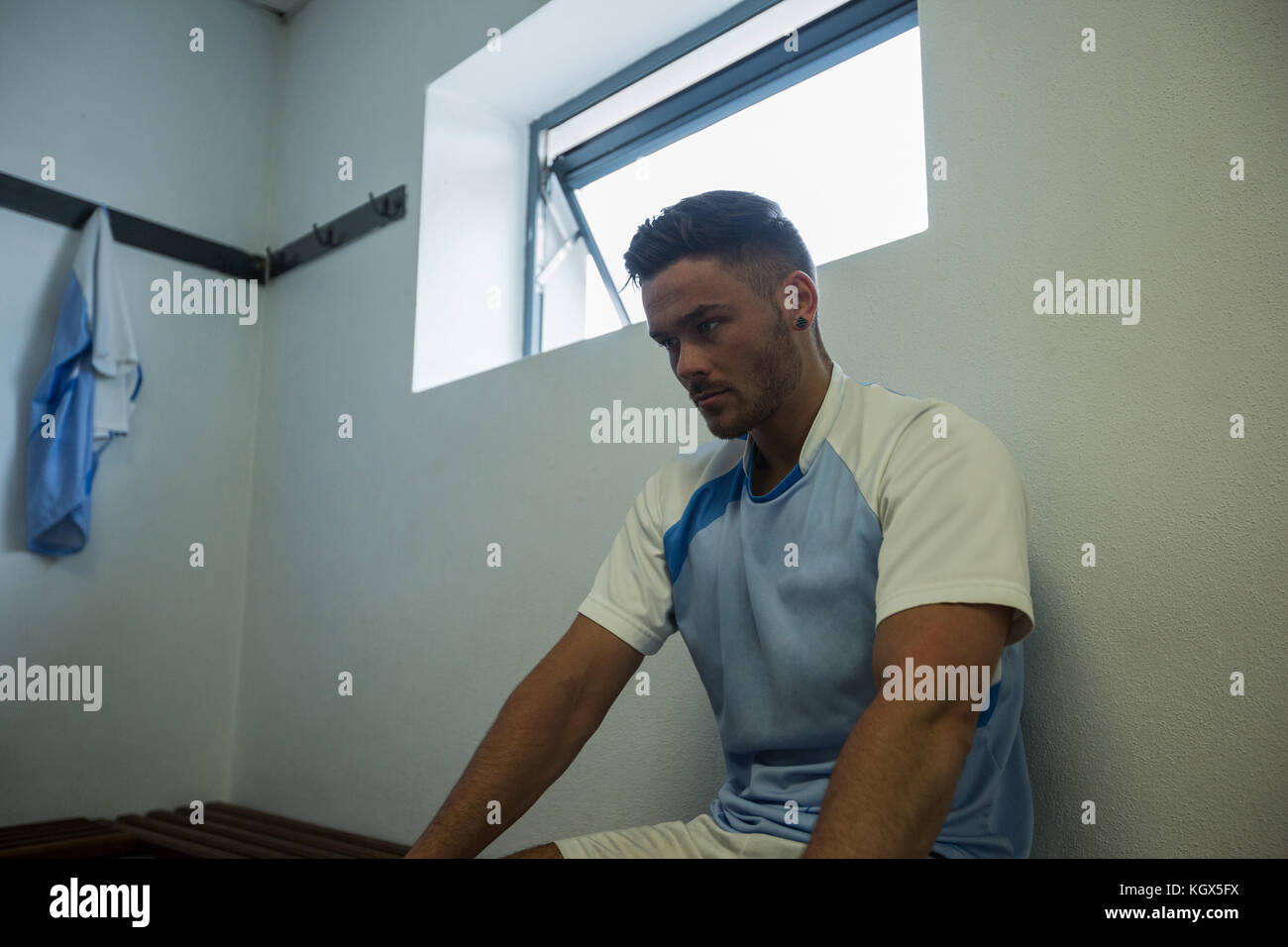 Sad football player sitting on bench in changing room Stock Photo - Alamy