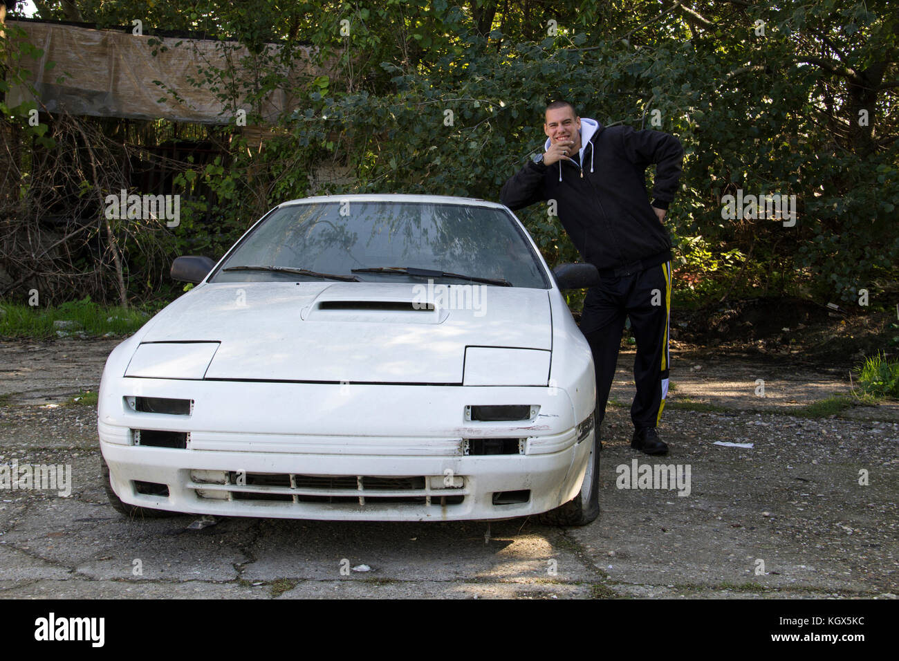 A young man, gopnik standing next to an abandoned car Stock Photo - Alamy