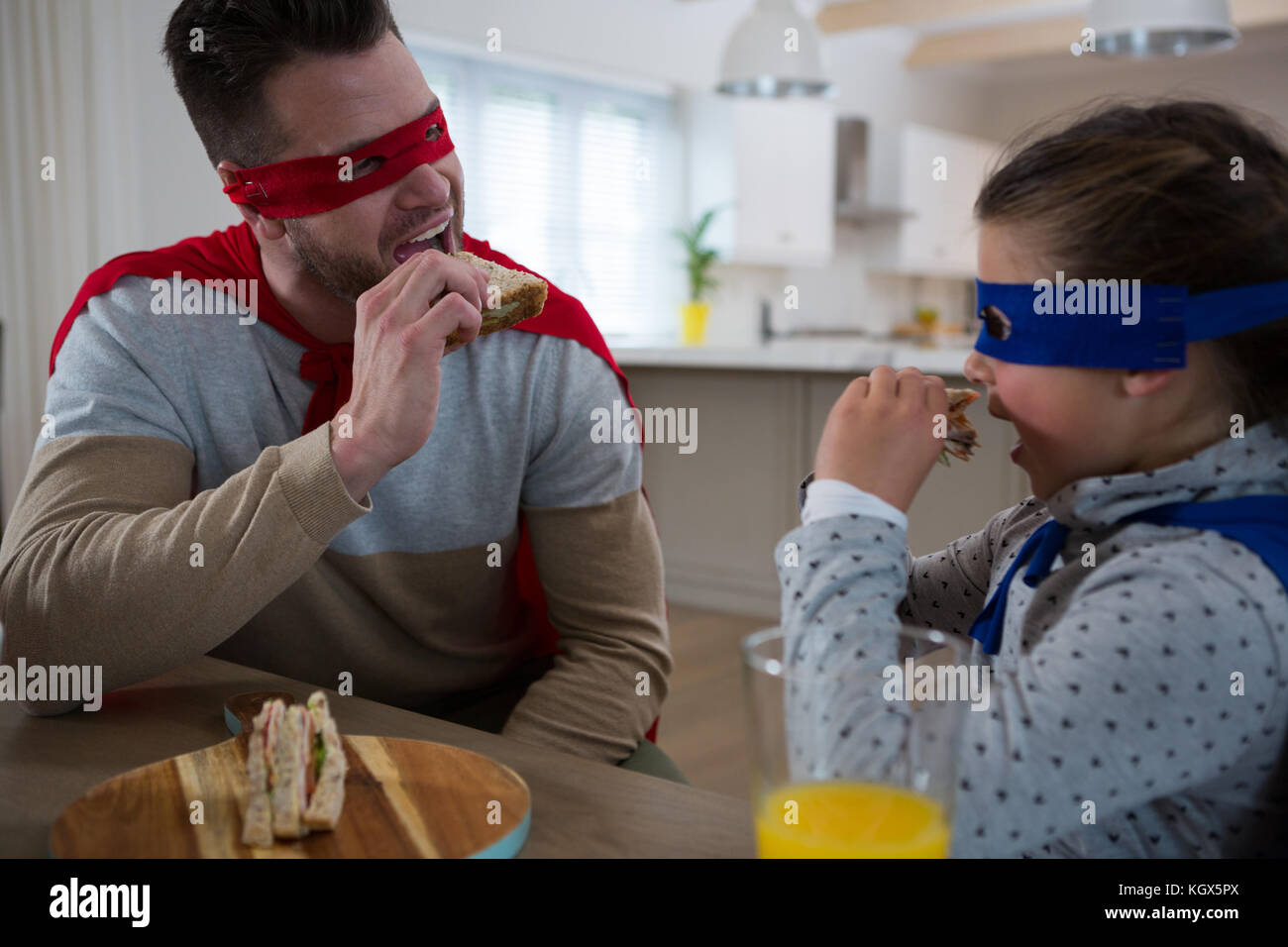 Father and daughter pretending to be superhero while having breakfast ...