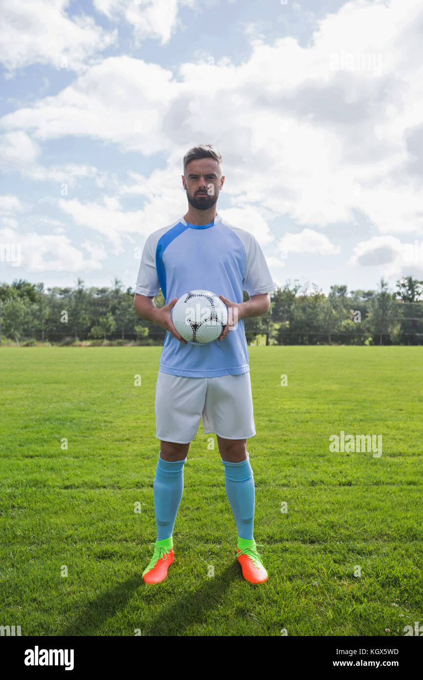 Portrait of football player holding soccer in the ground Stock Photo ...