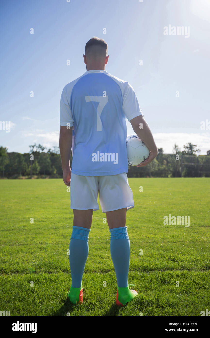 Rear view of football player with soccer ball standing in the ground ...