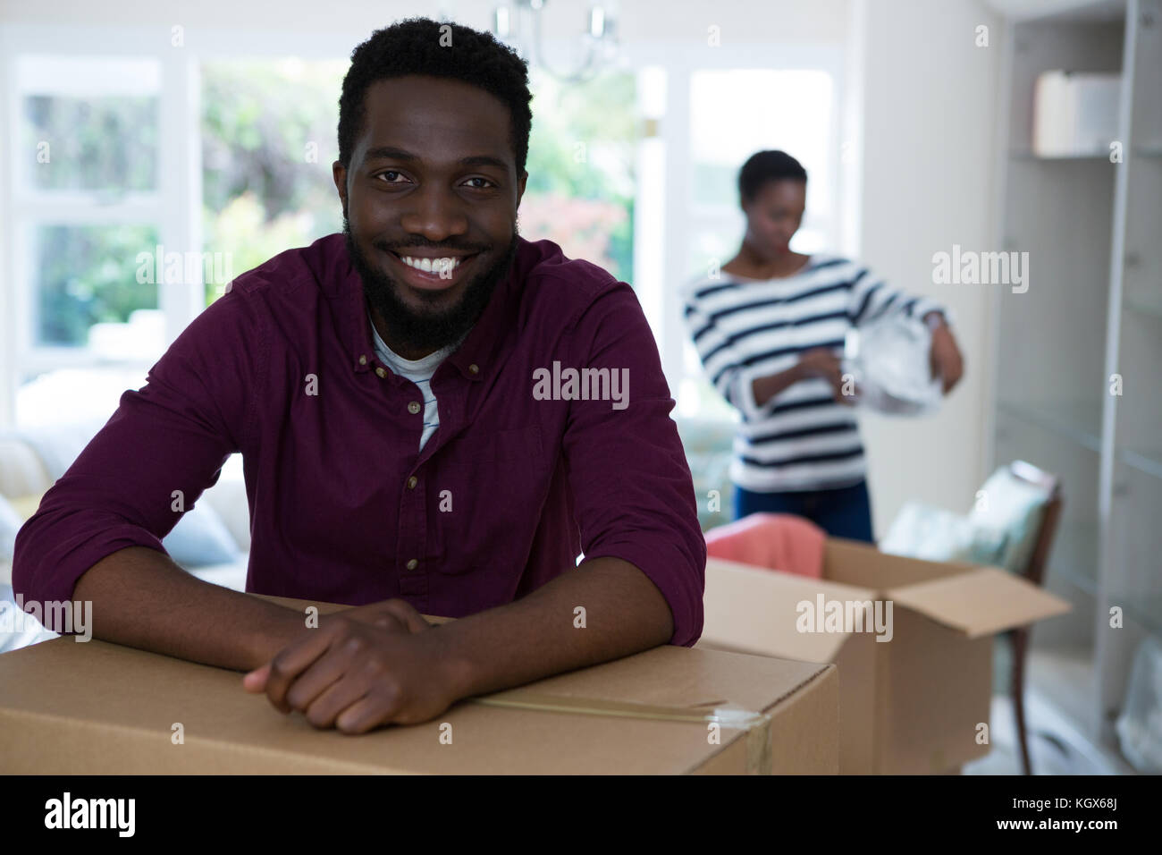 Portrait of happy man leaning on cardboard box Stock Photo - Alamy