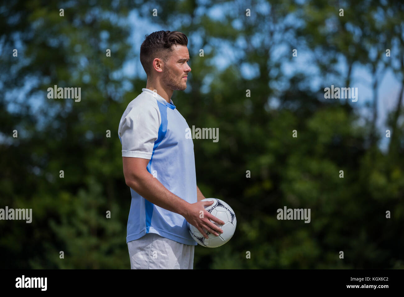 Side view of football player holding soccer in the ground Stock Photo ...