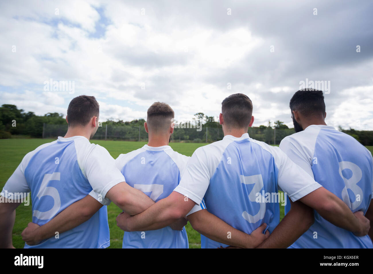 Rear view of football player standing together with arm around Stock ...