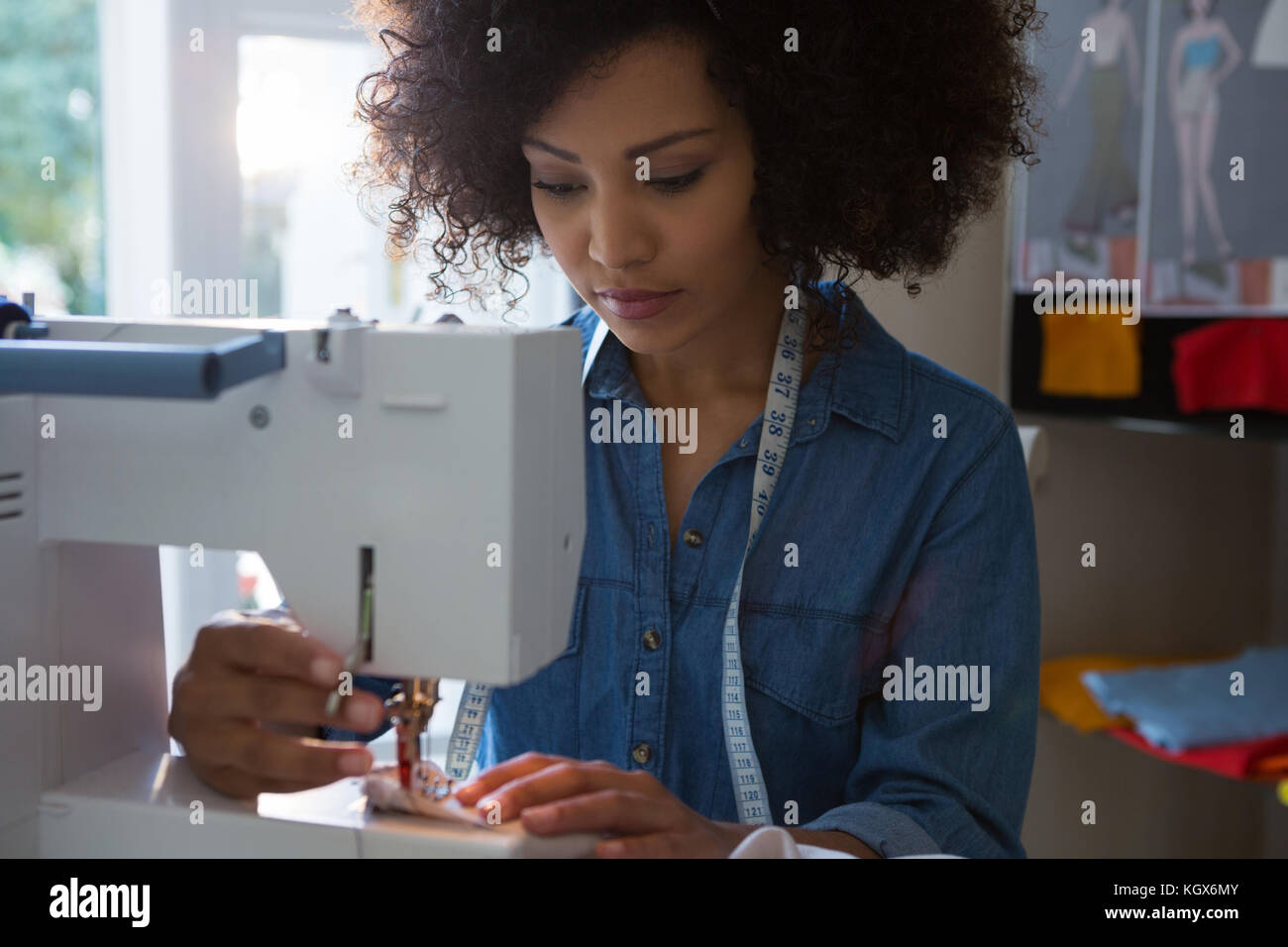 Female fashion designer stitching cloth in sewing machine at table ...