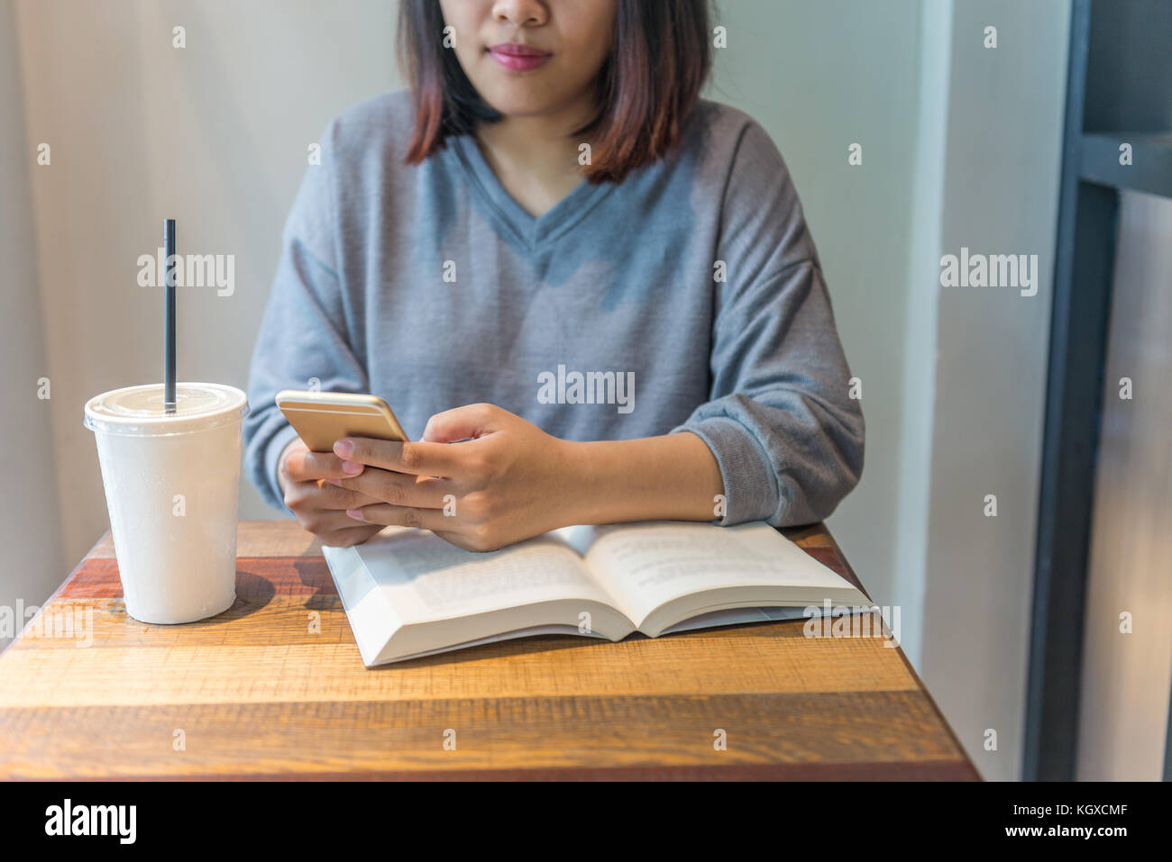 Young girl texting message, reading book in the library Stock Photo - Alamy