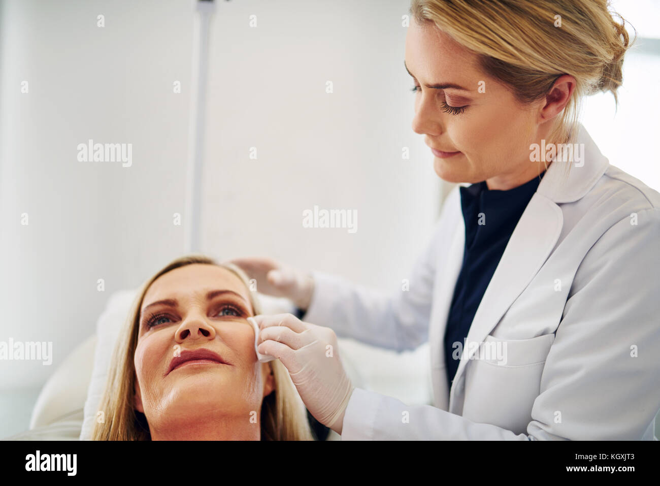 Young female doctor preparing the cheek of a mature woman lying on a ...
