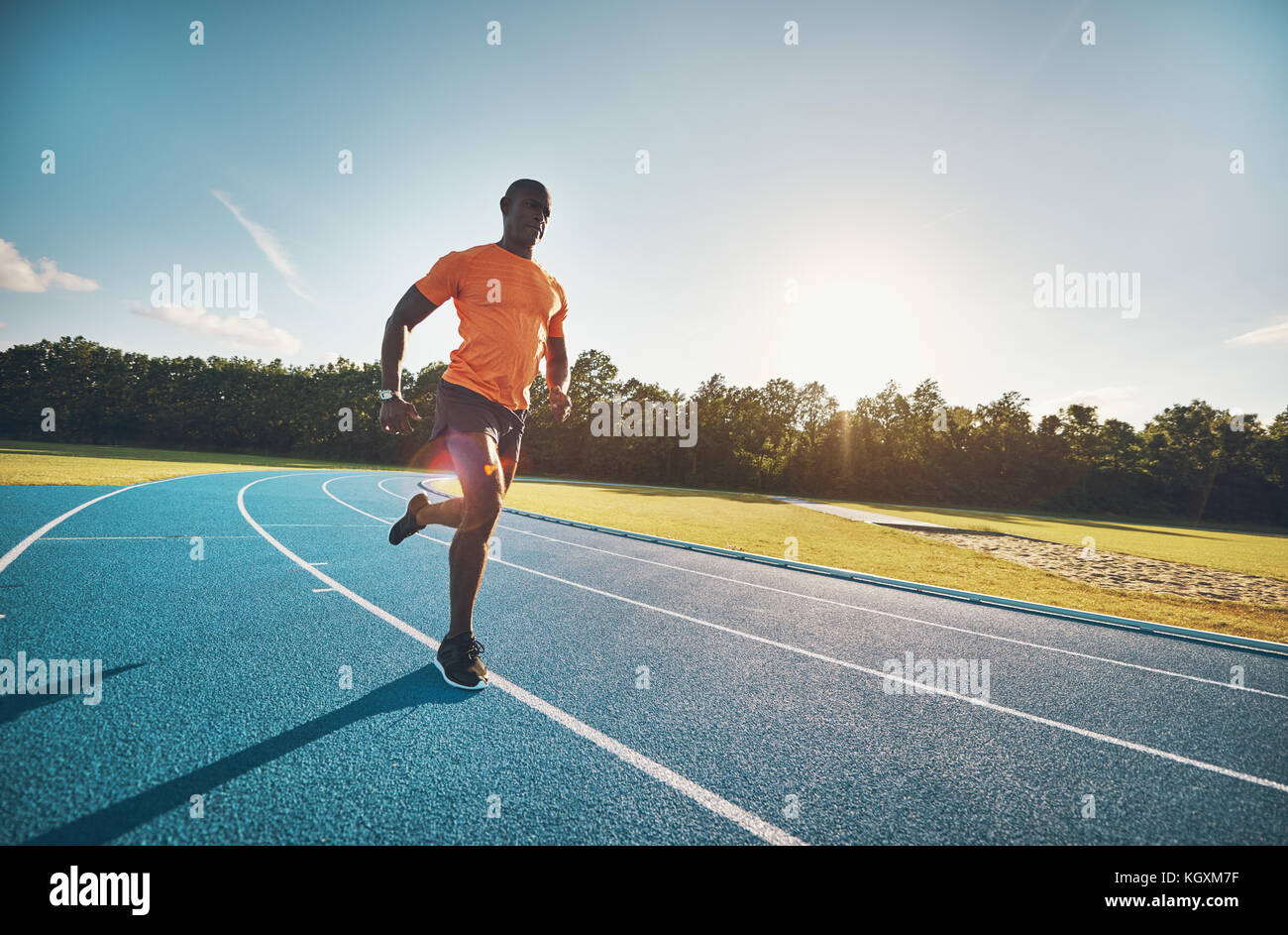 Focused young African male athlete in sportswear racing alone along a ...