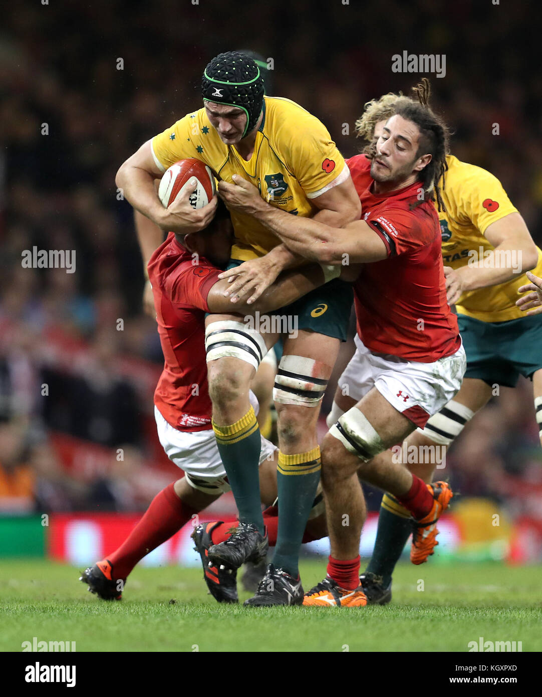Australia's Michael Hooper (centre) is tackled by Wales' Taulupe ...