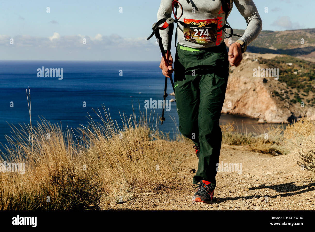male athlete runner with trekking poles runnning marine trail during ...