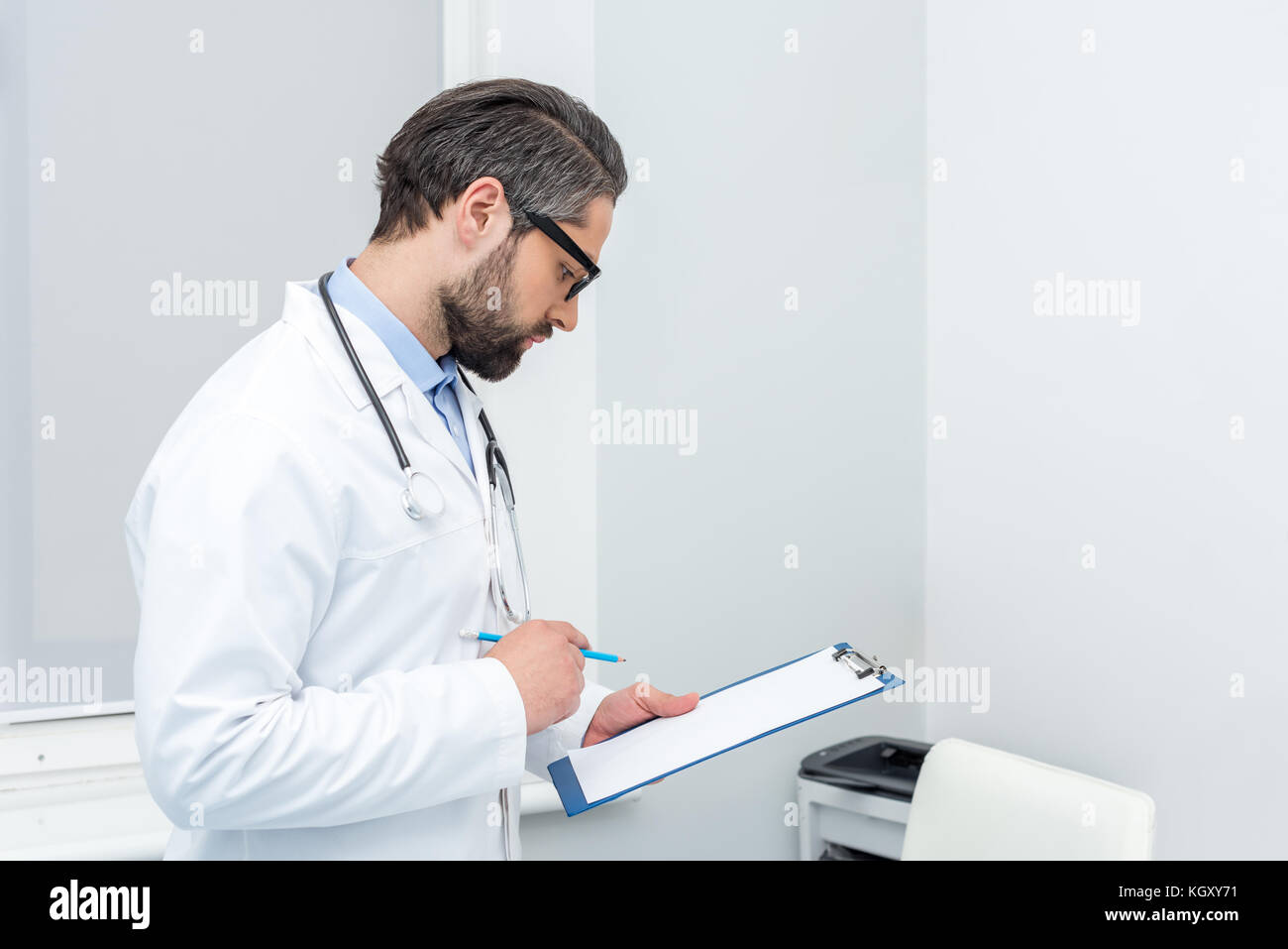 focused doctor looking at clipboard Stock Photo - Alamy