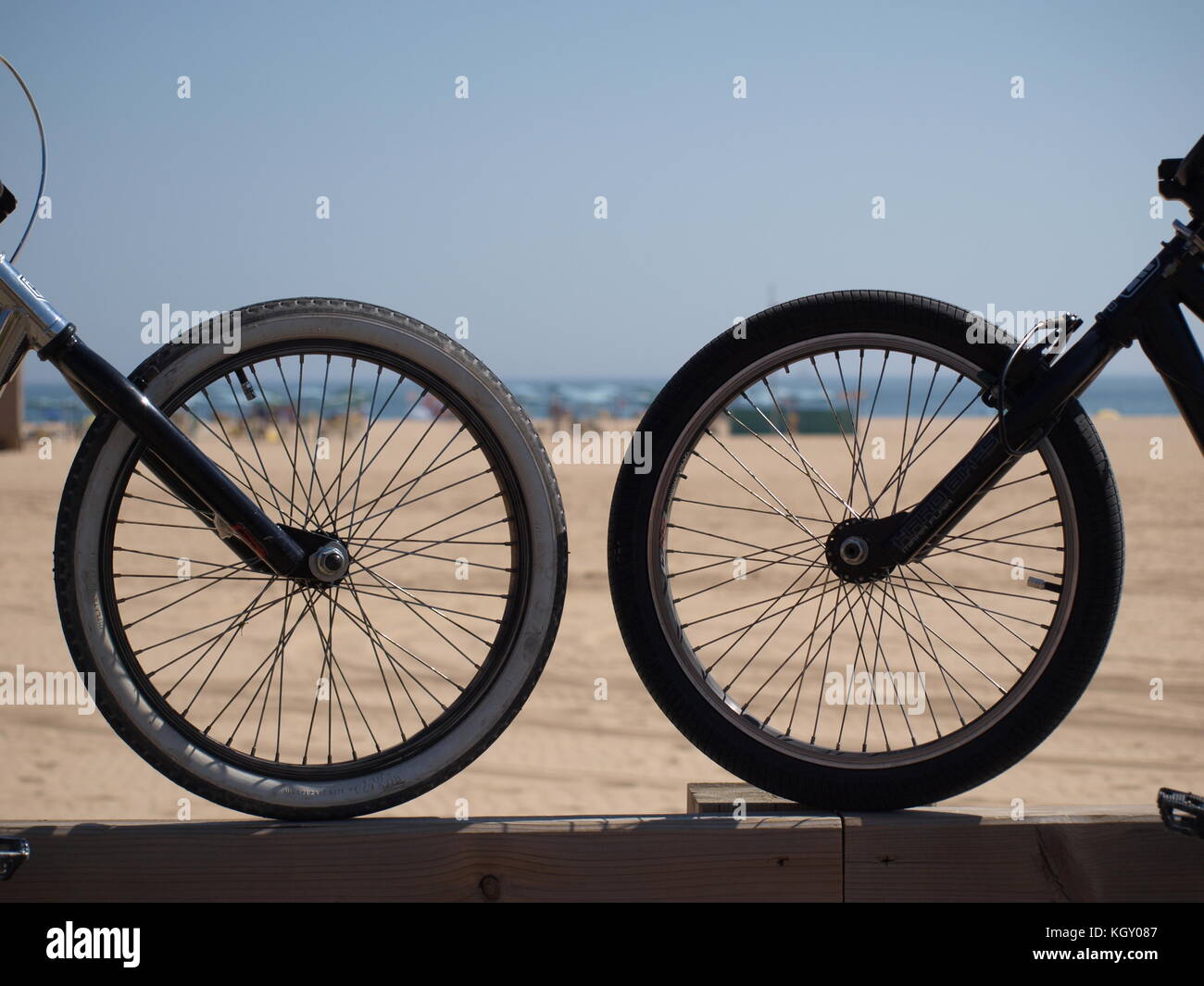 Two bicycle wheels facing each other on beach front Stock Photo - Alamy