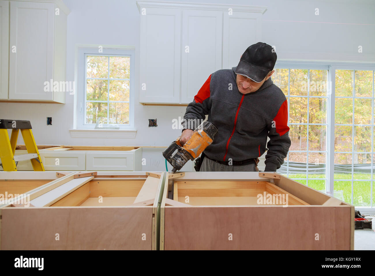 Young female carpenter using a nail gun while working in a workshop ...