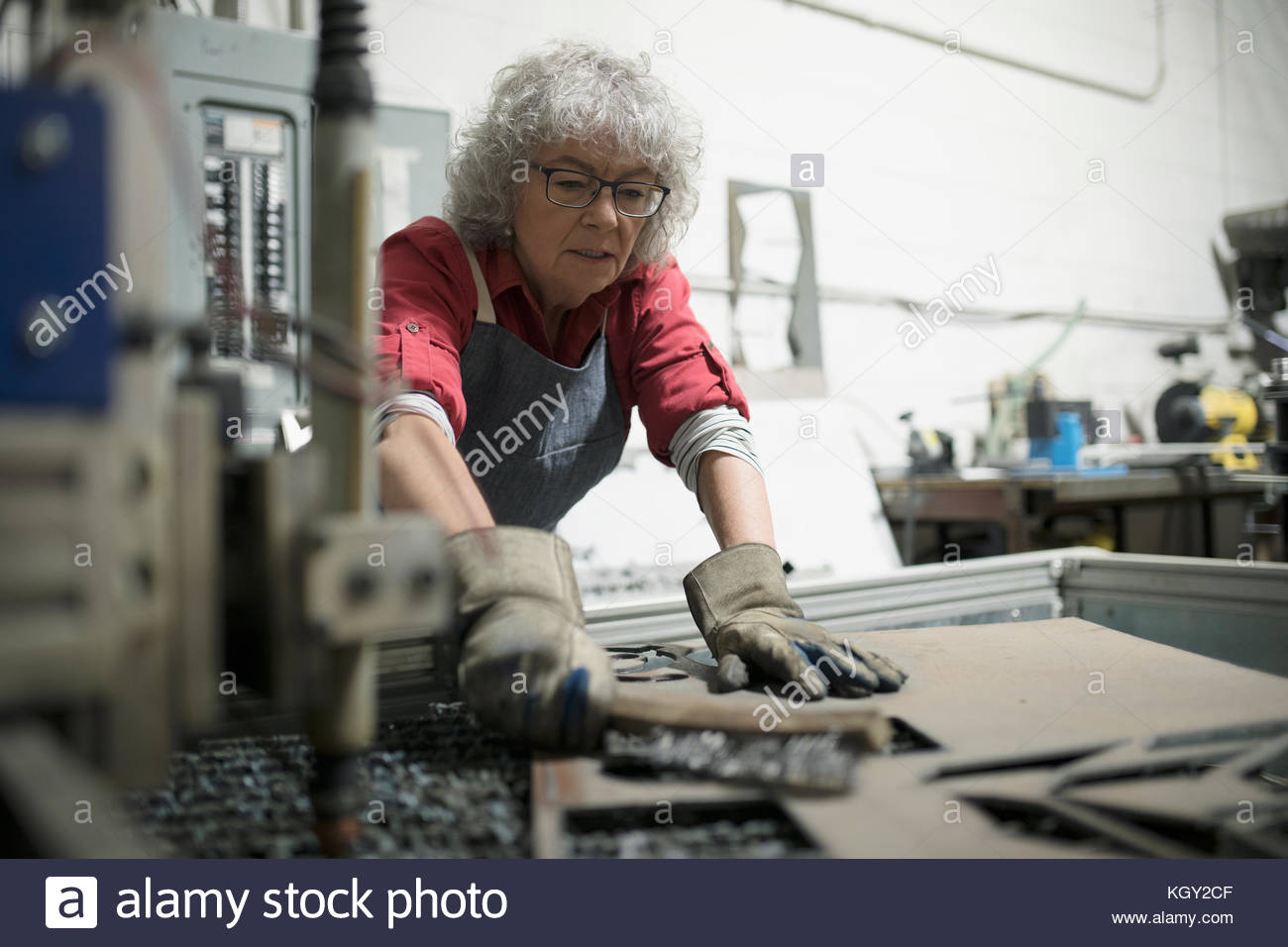 Senior female machinist using machinery in workshop Stock Photo - Alamy