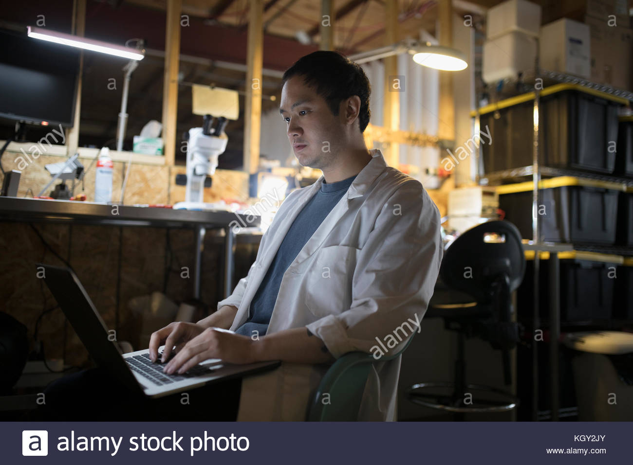 Focused male engineer working at laptop in dark workshop Stock Photo ...