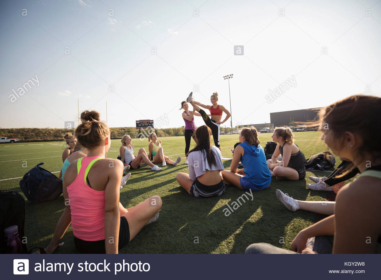 Teenage girl high school cheerleading team practicing on sunny football ...