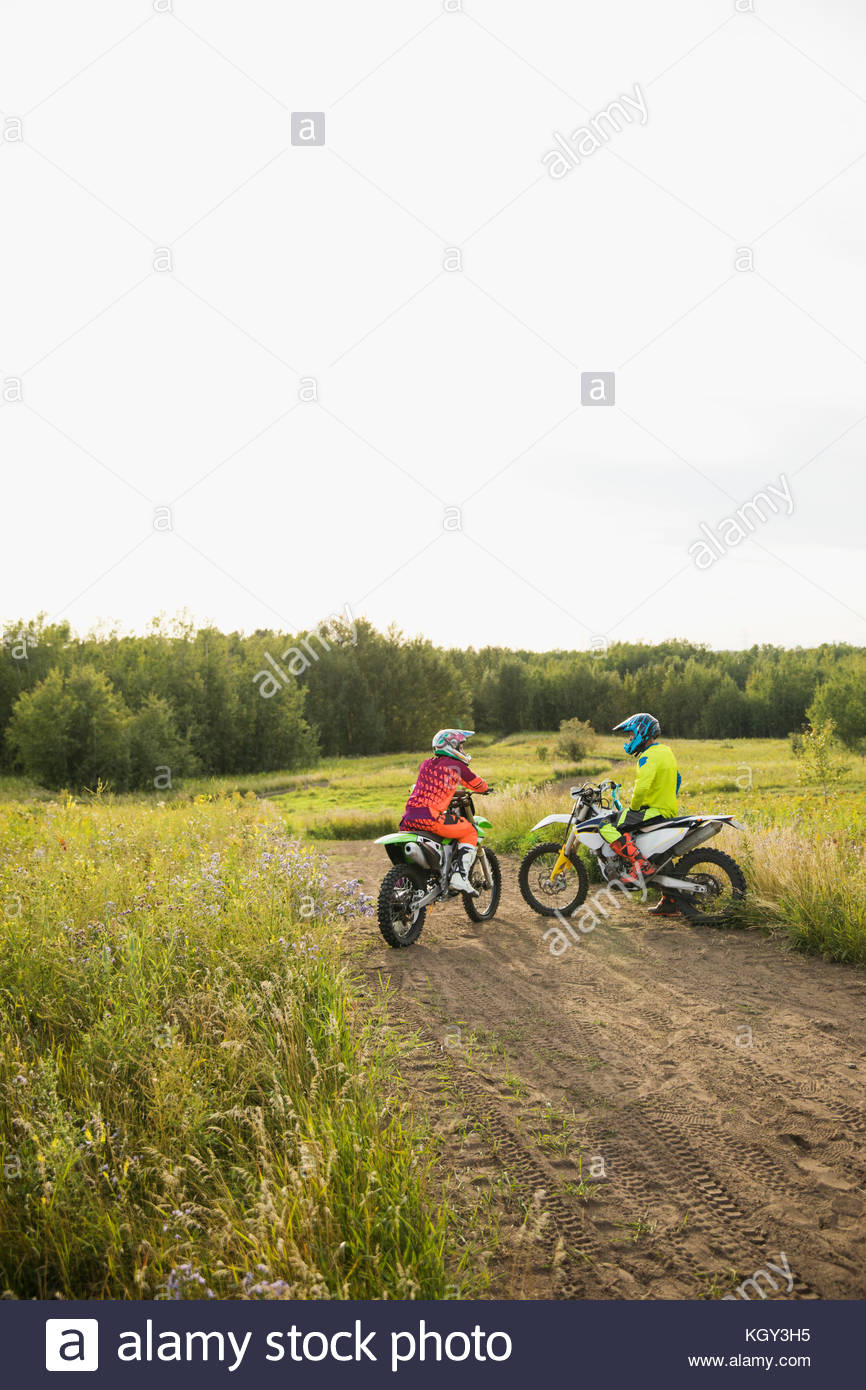 Male friends riding motorbikes on sunny rural dirt road Stock Photo - Alamy