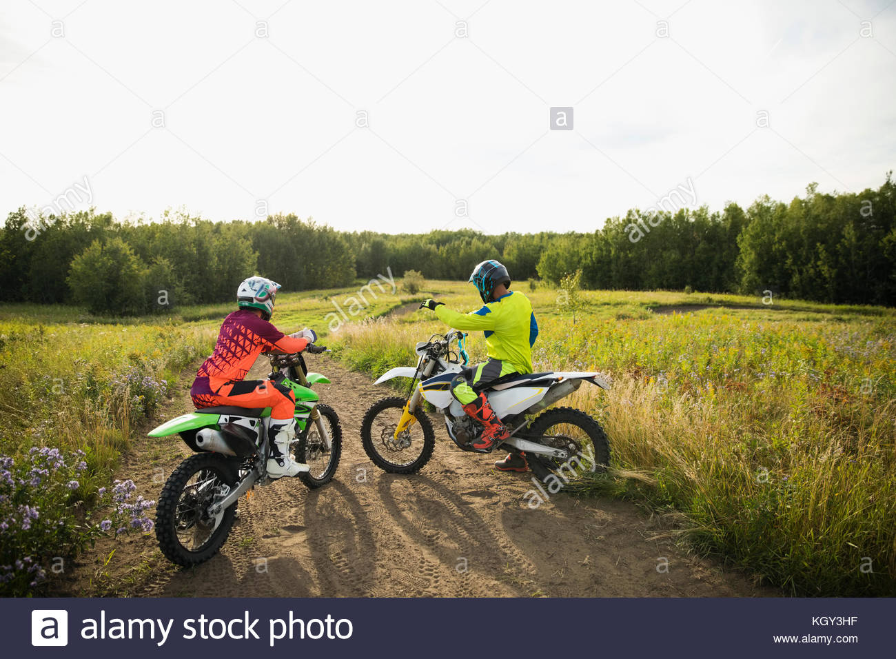 Male friends riding motorbikes on sunny rural dirt road Stock Photo - Alamy