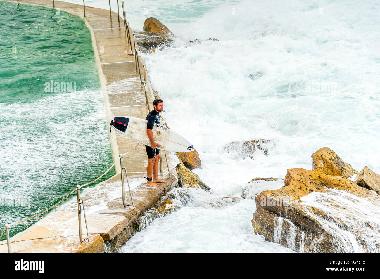 A surfer waits for the right time to enter the water from the Bronte ...