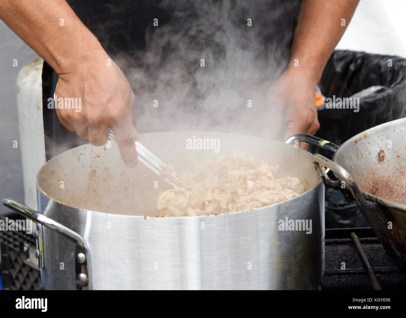 Close up on male hands mixing hot steaming chicken mashed in a large ...