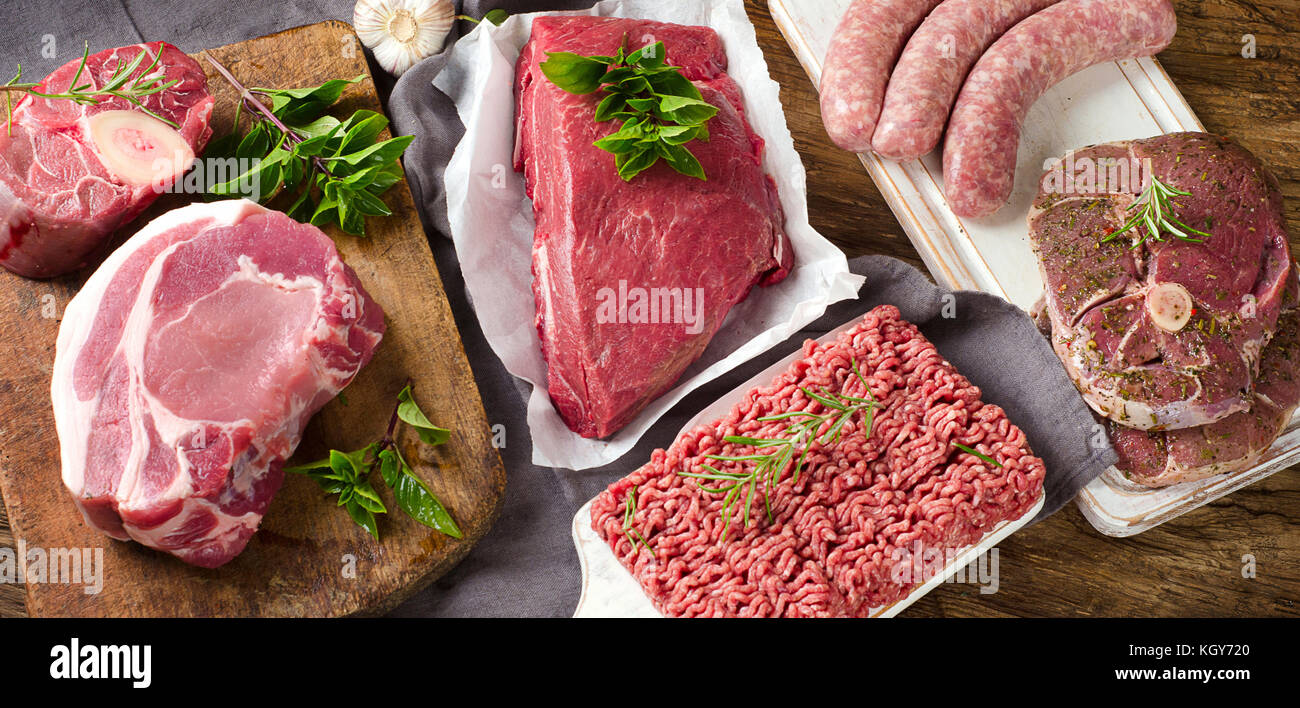 Different types of fresh raw meat on dark wooden background. Banner ...