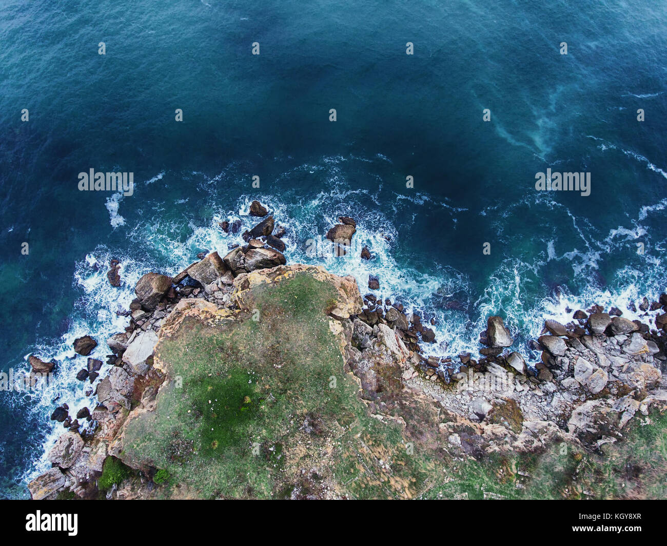 Aerial view of rocky coastline with crop fields and crashing ocean ...