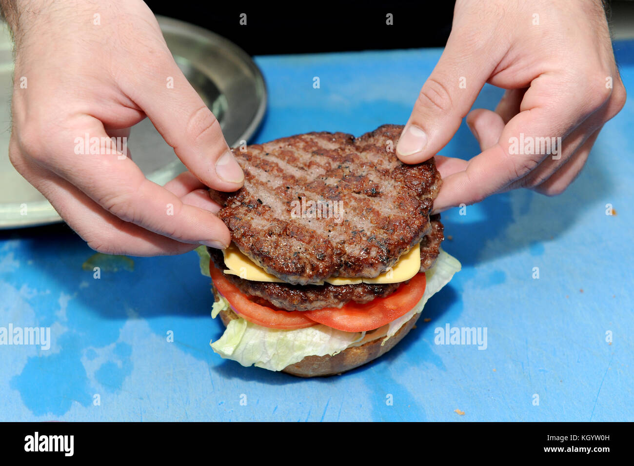 Cook adding burger on prepared buns for hamburger. Preparing and making ...