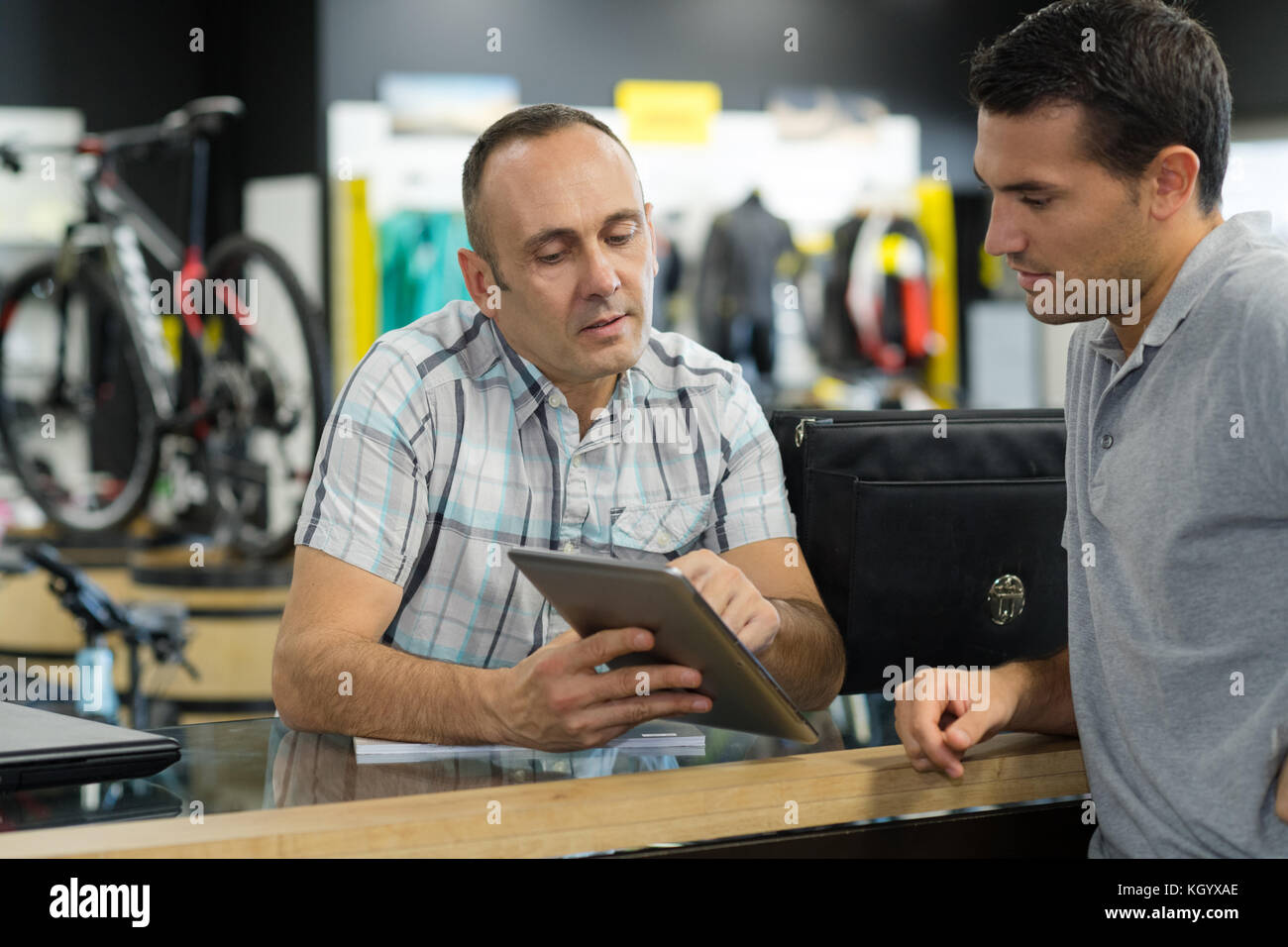 Men at shop counter looking at tablet Stock Photo - Alamy