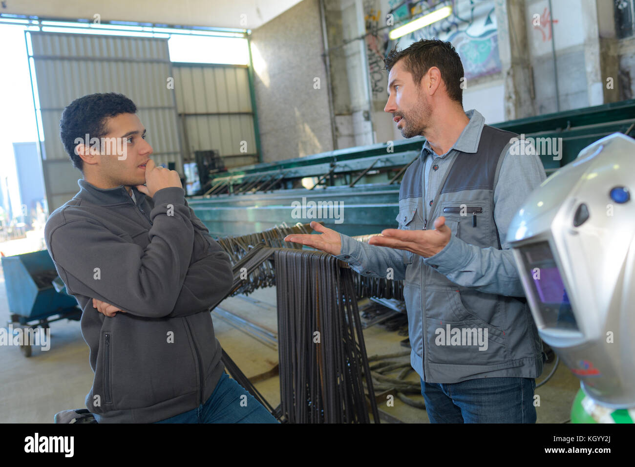 Two men talking in industrial factory Stock Photo - Alamy