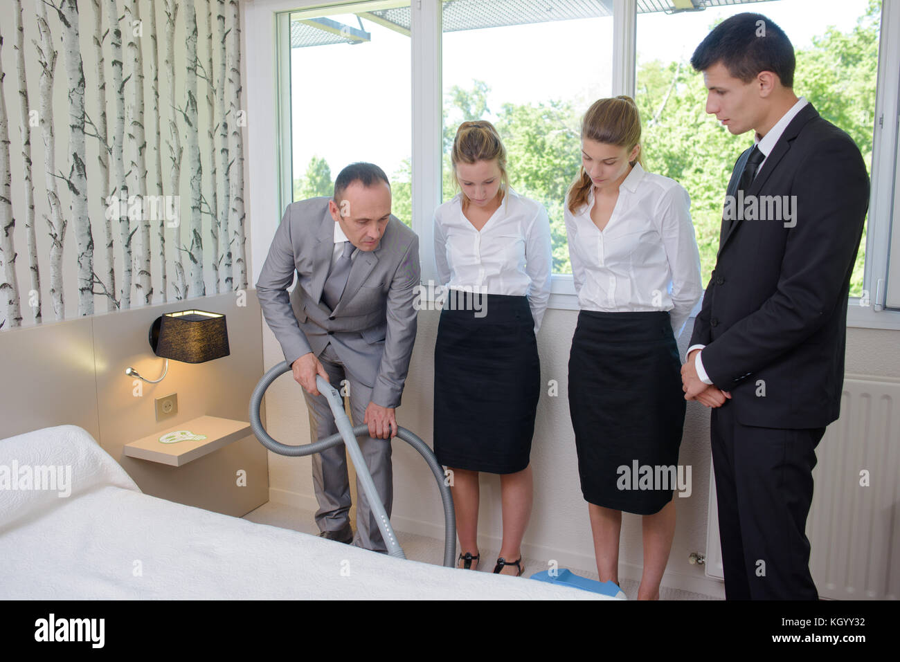 Man showing chamber maids how to vacuum Stock Photo - Alamy