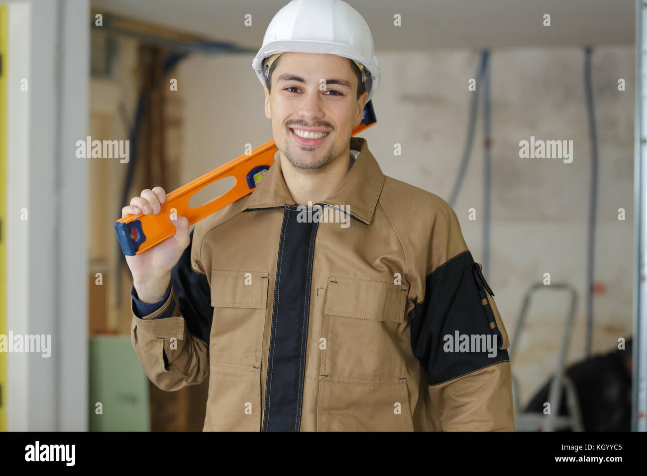 professional builder posing with spirit level at construction site ...