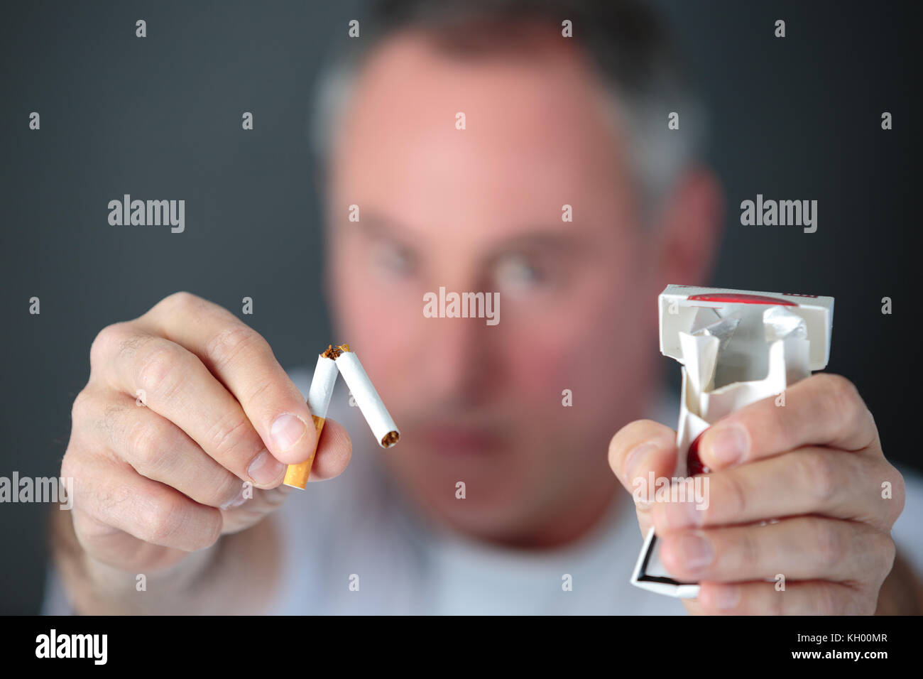 one fist breaking cigarette packet and the other a cigarette Stock ...