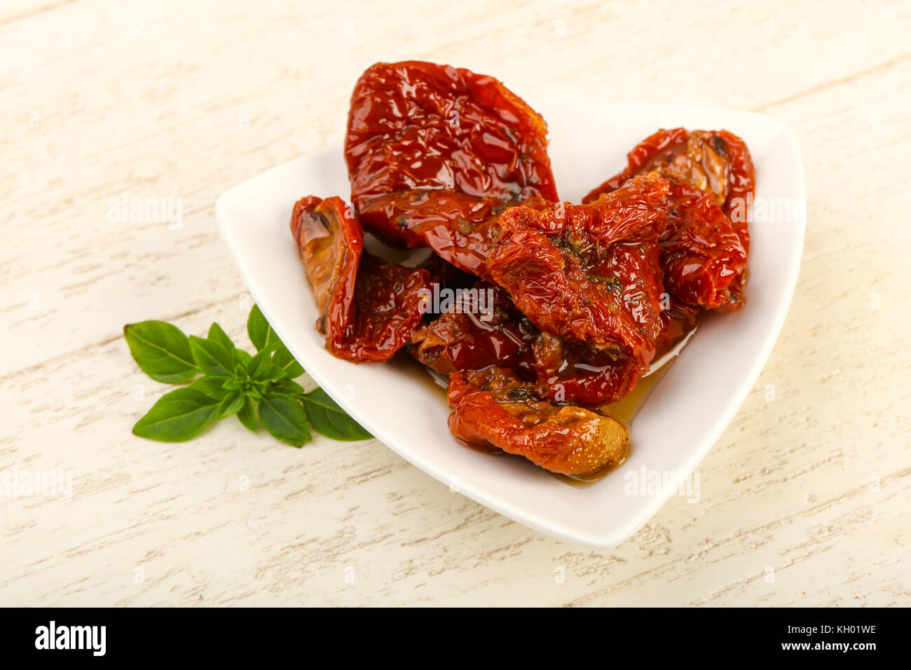 Dried tomato in olive oil with basil leaves Stock Photo - Alamy