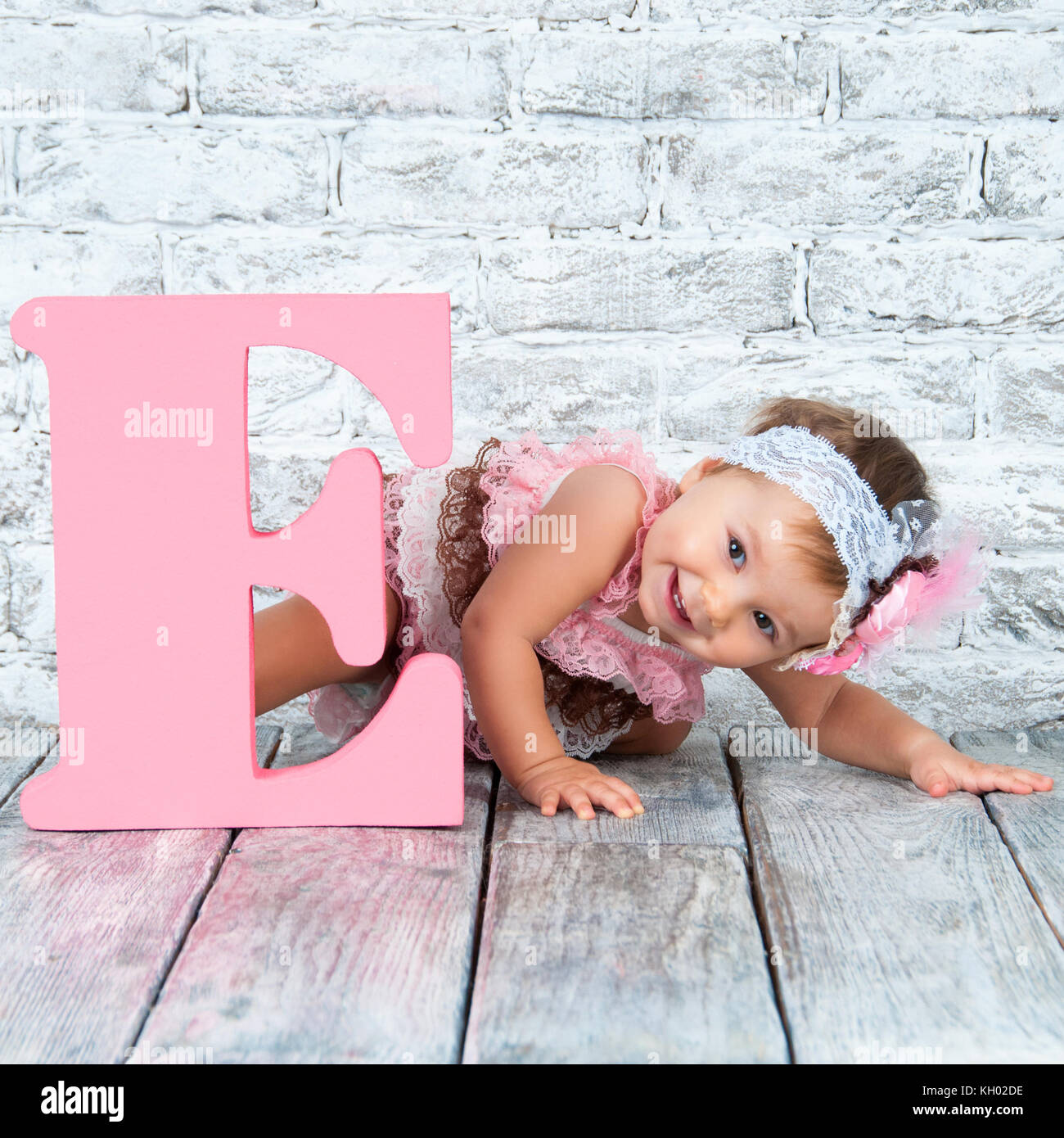 Beautiful and cute girl in pink dress with the letter E. Emotional girl ...